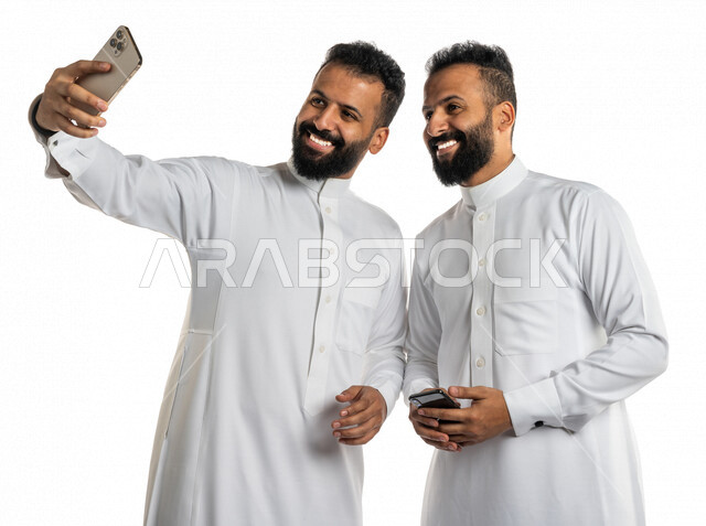 Portrait of two Saudi Arabian Gulf twin men enjoying taking a selfie ...