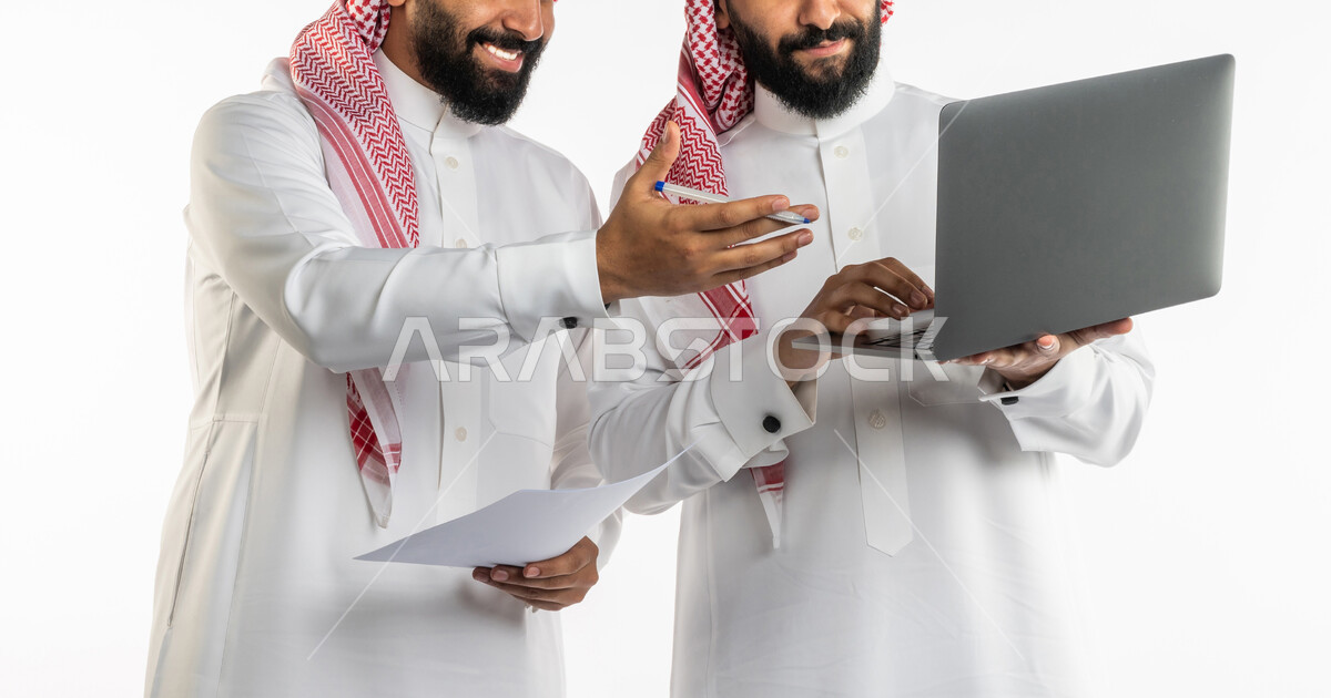 Portrait of two Saudi Arabian Gulf twin men discussing work tasks, co ...
