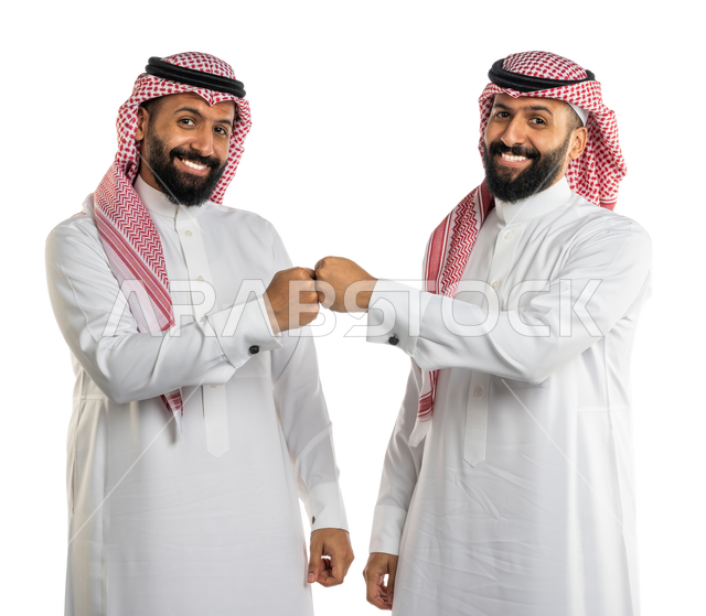 Portrait of two Saudi Arabian Gulf twin men, striking the fist with the ...