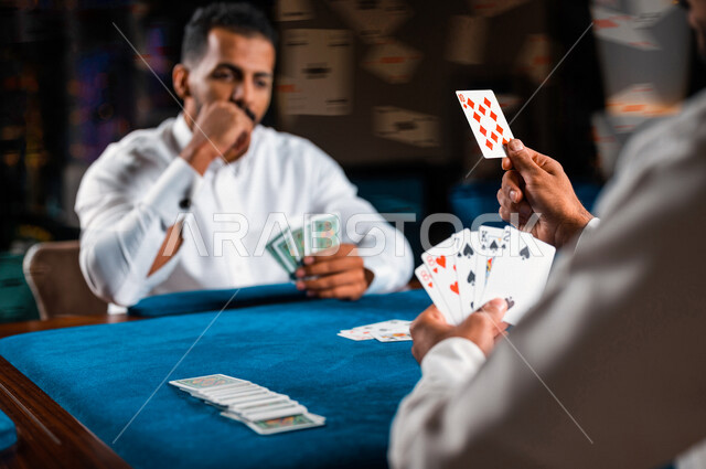 A close-up of two Saudi Arabian Gulf youths playing a card game in one ...