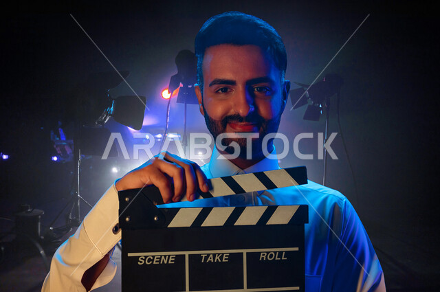 A Saudi Arabian Gulf man inside the filming location, holding a film in ...