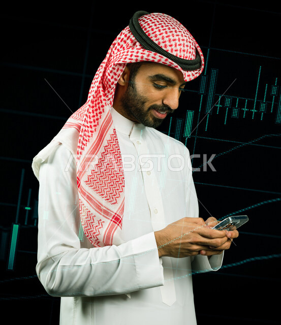 A Saudi Arabian Gulf man using a mobile phone, stock exchange ...