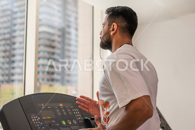 A Saudi Arabian Gulf man wears sports clothes and walks on the electric ...