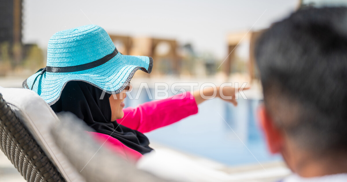 زوجان عربيان خليجيان سعوديان يجلسان على كرسي الاستلقاء ، سيدة خليجية