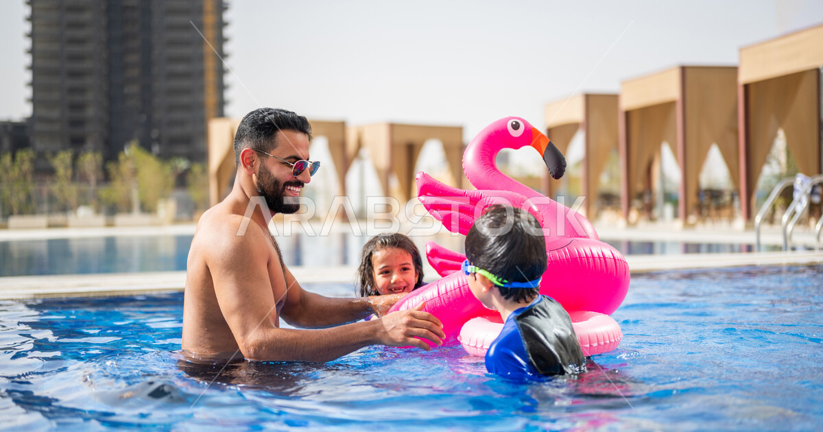 A Saudi Arabian Gulf family enjoying swimming in the swimming pool ...