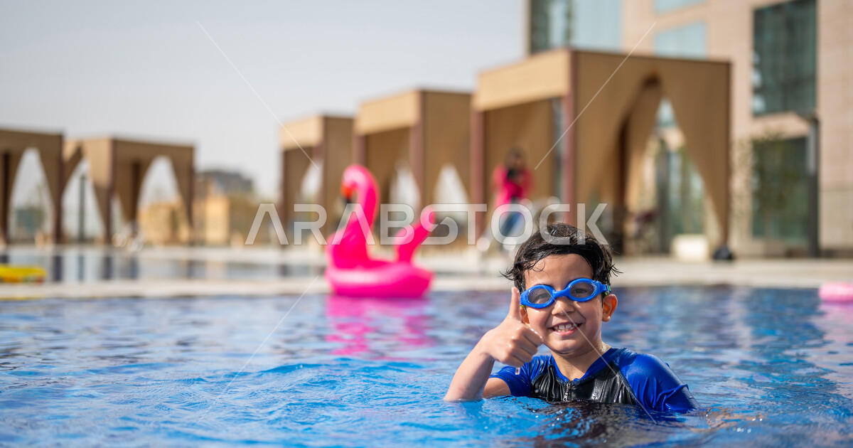 A smiling and happy Saudi Arabian Gulf child wearing a swimsuit and ...