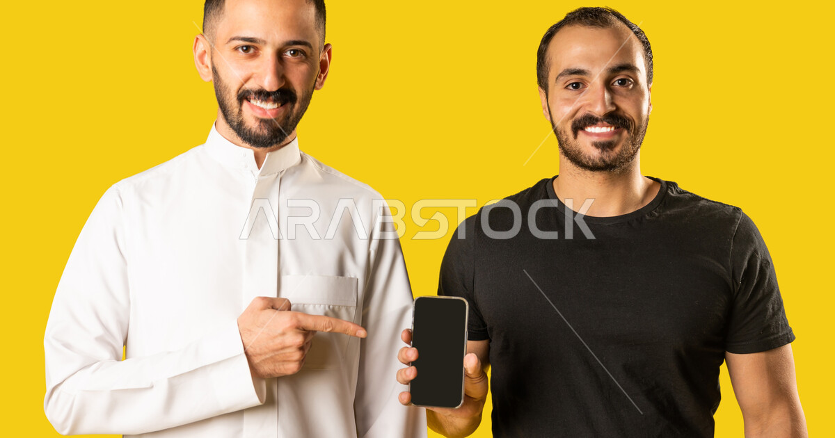 Portrait of two Saudi Arabian Gulf men, one of them holding a mobile ...