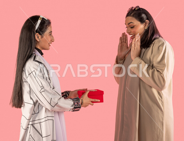 Portrait of a Saudi Arabian Gulf woman presenting a gift to her mother ...