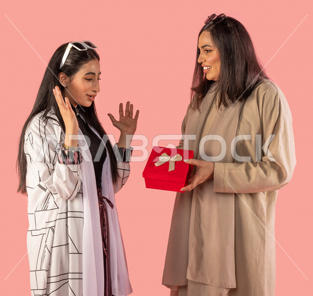 Portrait of a smiling Saudi Arabian Gulf woman giving her daughter a ...