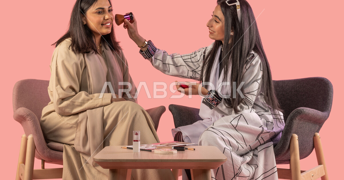 Portrait of two Saudi Arabian Gulf women, a young Saudi woman applying ...