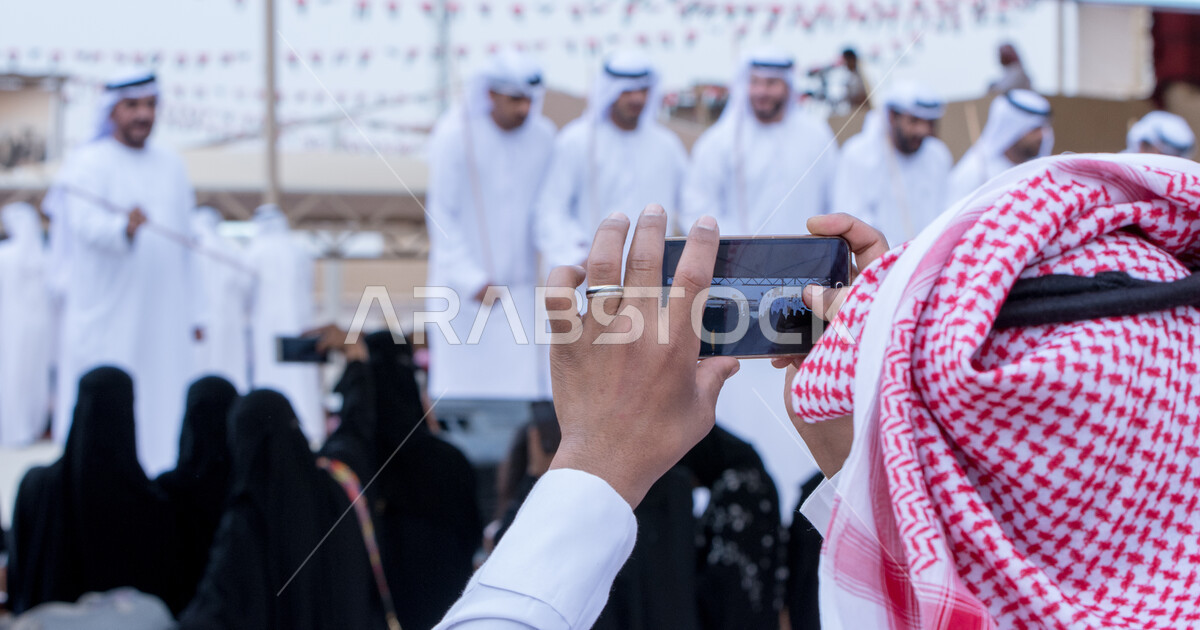 A group of Emirati Gulf Arab men dance the Ayala dance (stick dance) in ...