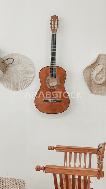 A picture of a musical instrument hanging on a white wall, a hat and ...