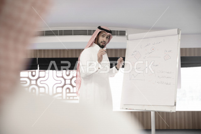 A Saudi Arabian trainer explains to Saudi Gulf trainees on a whiteboard ...