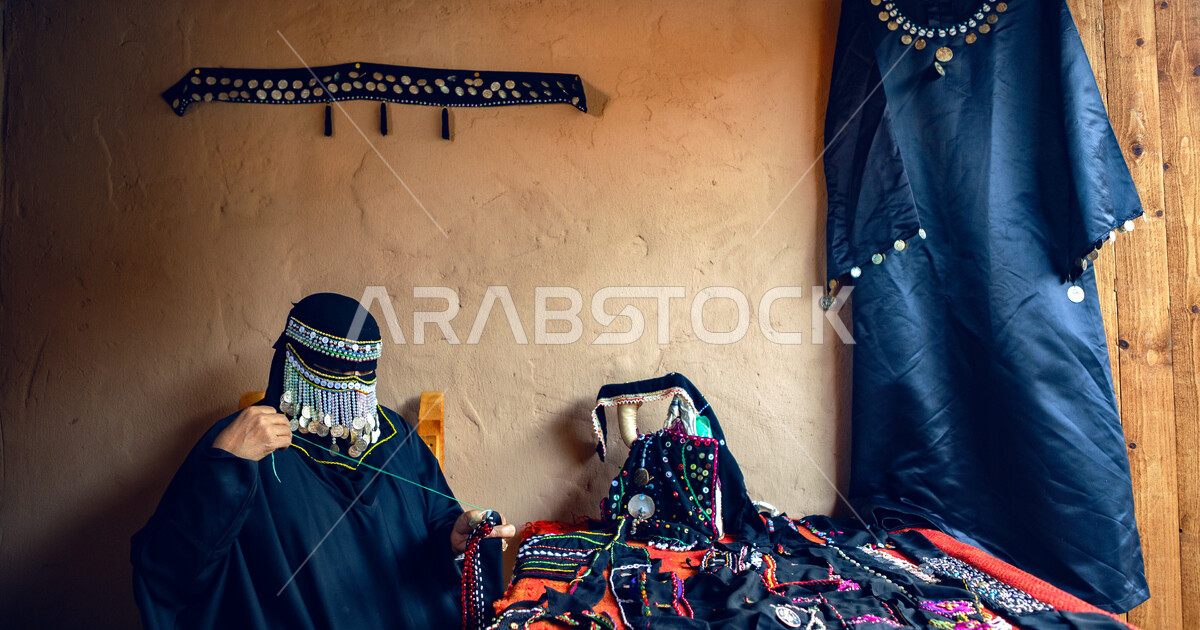 A veiled Saudi Arabian Gulf woman doing sewing, handicrafts, sewing of ...