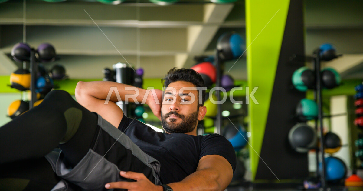 A Saudi Arabian Gulf youth doing exercises on a yoga mat, strengthening ...