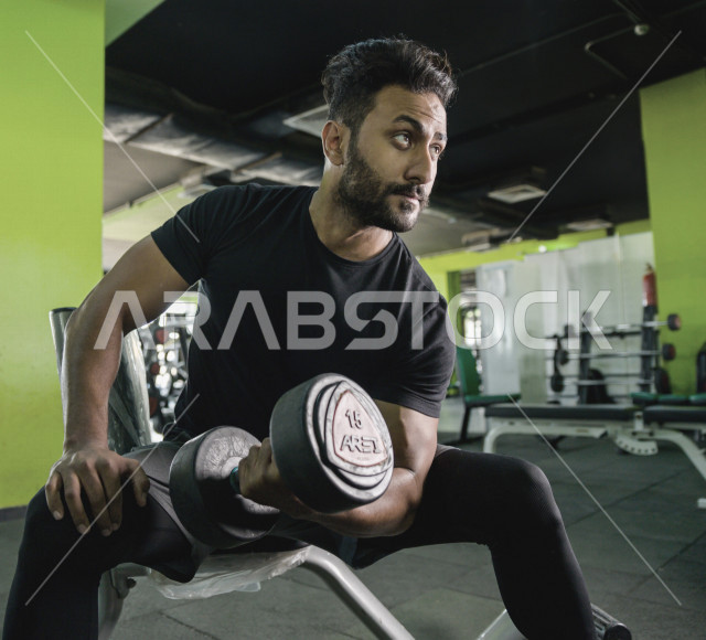 A young Saudi Arabian Gulf man is practicing weightlifting in the iron ...