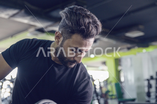 A young Saudi Arabian Gulf man is practicing weightlifting in the iron ...
