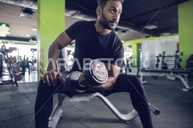 A young Saudi Arabian Gulf man is practicing weightlifting in the iron ...