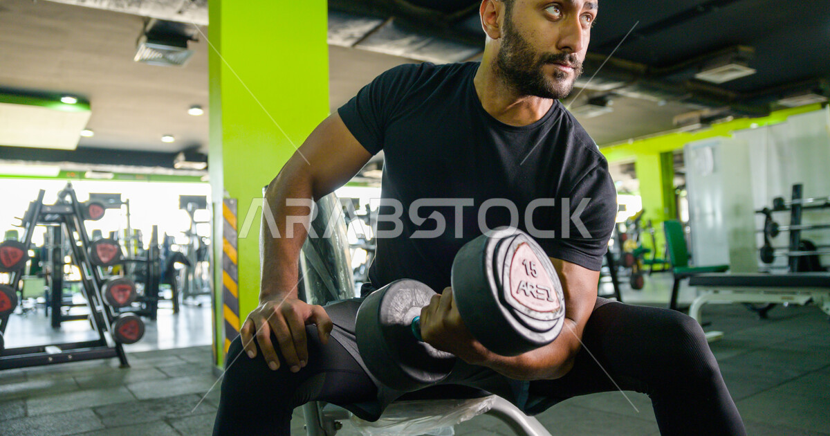 A young Saudi Arabian Gulf man is practicing weightlifting in the iron ...