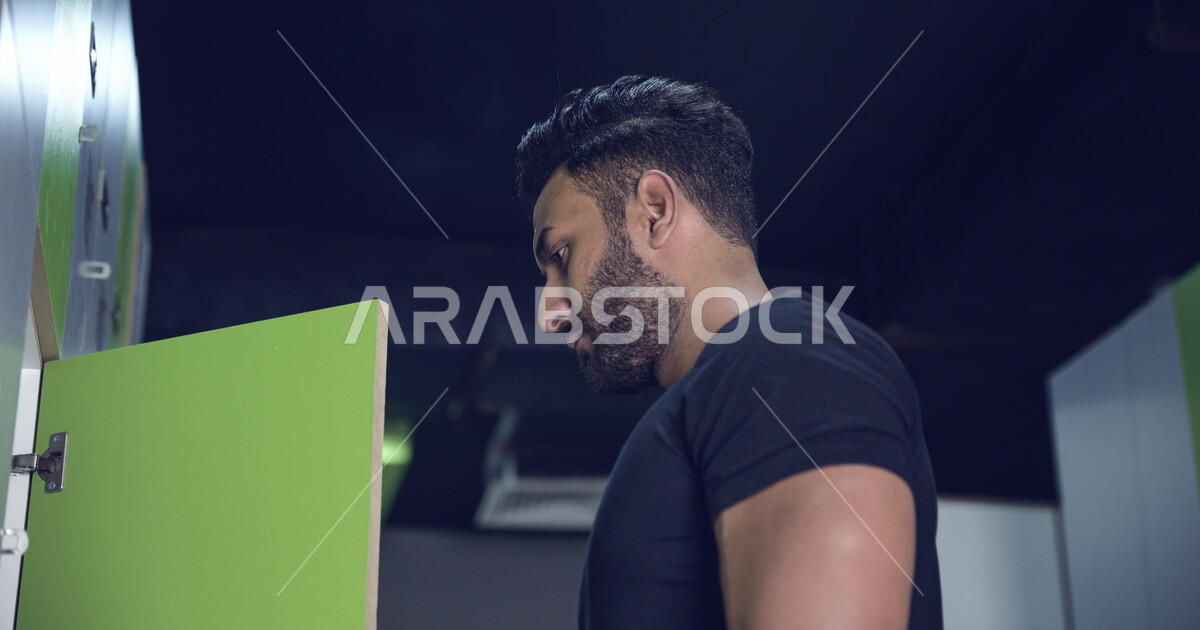 A young Saudi Arabian Gulf man opens the locker and prepares for ...