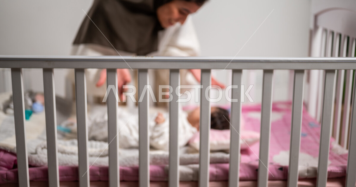 A Saudi Arabian Gulf mother with her infant child lying in the cradle ...