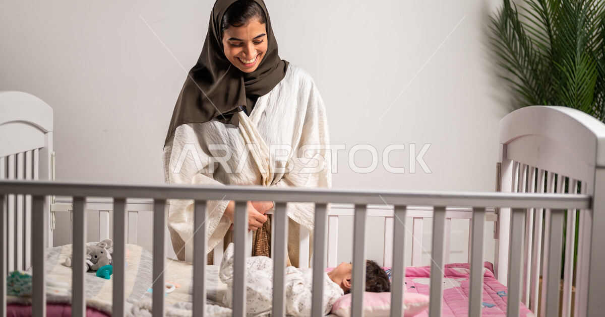 A Saudi Arabian Gulf mother with her infant child lying in the cradle ...