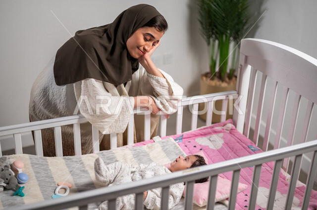 A Saudi Arabian Gulf mother with her infant child lying in the cradle ...