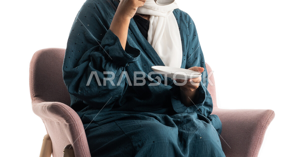 Portrait of a Saudi Arabian Gulf woman sitting on a chair holding a ...