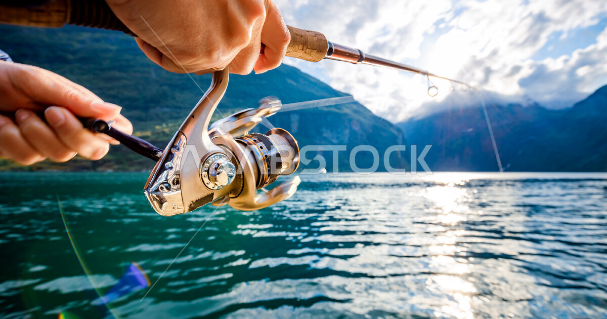 صورة مقربة ليد رجل يقوم بصيد الأسماك في البحر , هواية صيد السمك , سنارة ...