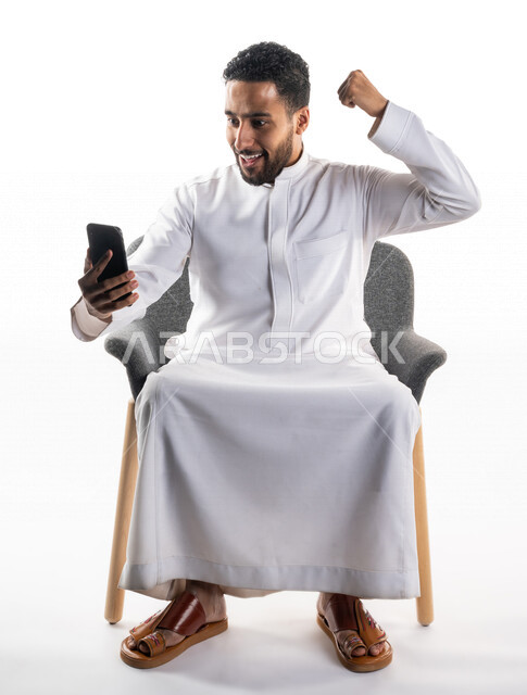 Portrait of a Saudi Arabian Gulf man wearing a Saudi dress, sitting on ...
