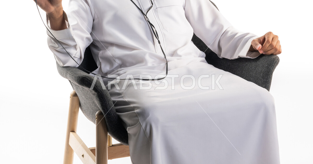 Portrait of a Saudi Arabian Gulf man in Saudi dress sitting on a chair ...