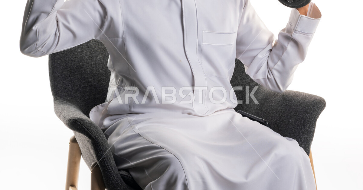 Portrait of a Saudi Arabian Gulf man sitting on a chair doing exercises ...