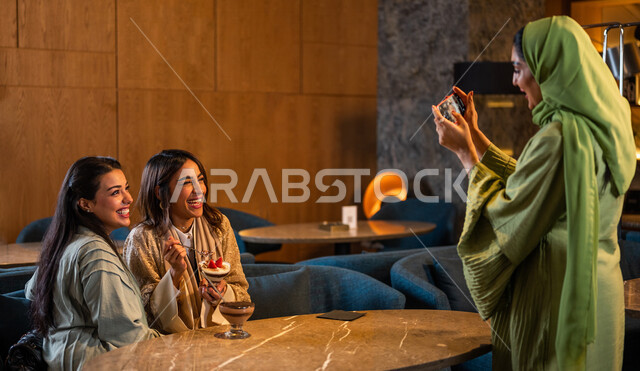 Saudi Gulf Arab female friends sitting in the cafe, taking memorial ...