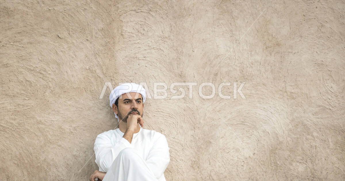 Emirati Gulf Arab man, in traditional Emirati dress, sitting on the ...