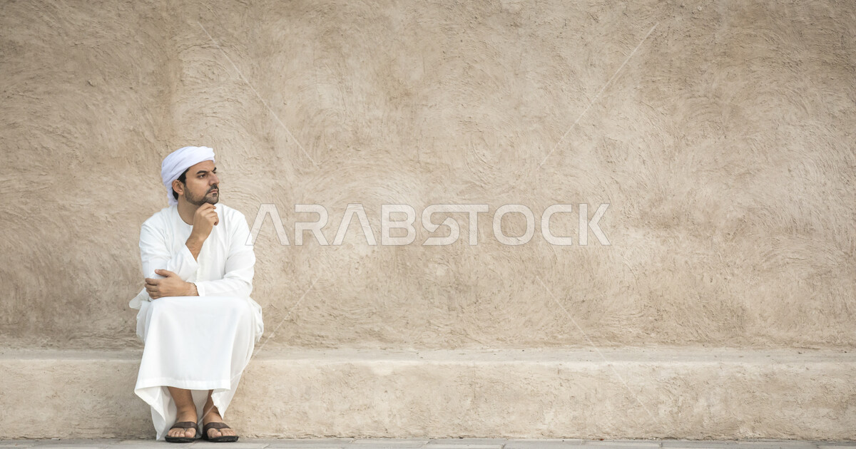 Emirati Gulf Arab man, in traditional Emirati dress, sitting on the ...