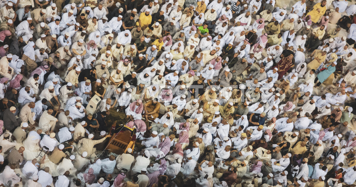 A group of men gathered around the imam of the Grand Mosque listening ...