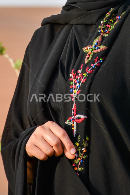 A Gulf Arab woman wearing a black abaya, a close-up of a Gulf Arab ...