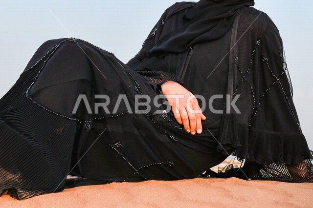 A Gulf Arab woman wearing a black abaya, a close-up of a Gulf Arab ...