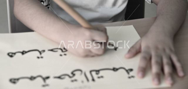 A Saudi Arabian Gulf child writes the phrase “Himma to the top” in ...