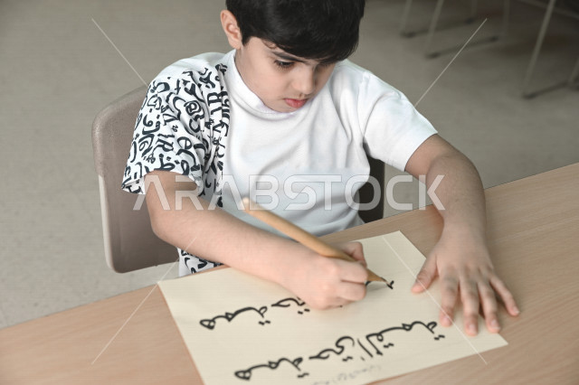 A Saudi Arabian Gulf child writes the phrase “Himma to the top” in ...
