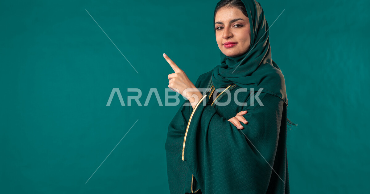 كروما، مرأة عربية خليجية سعودية محجبة أنيقة ومتألقة، تشير بإصبعها لأعلى