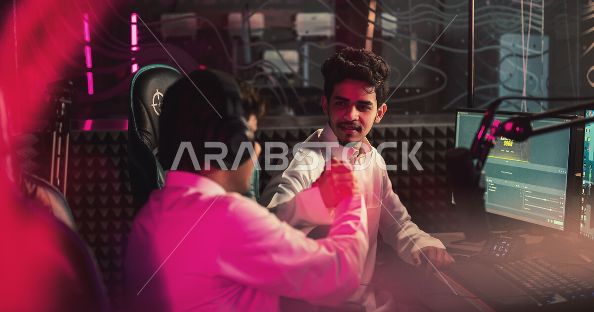 Two young Saudi Arabian Gulf teenagers shaking hands in an electronic ...