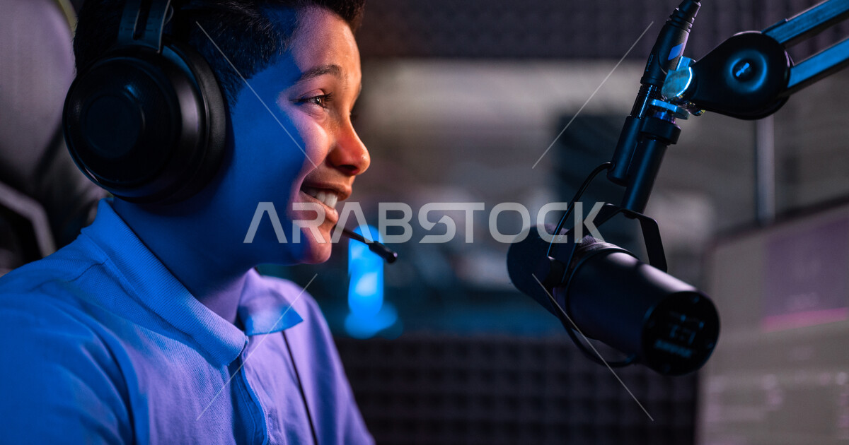 A Saudi Arabian Gulf boy in an electronic game store, wearing a headset ...