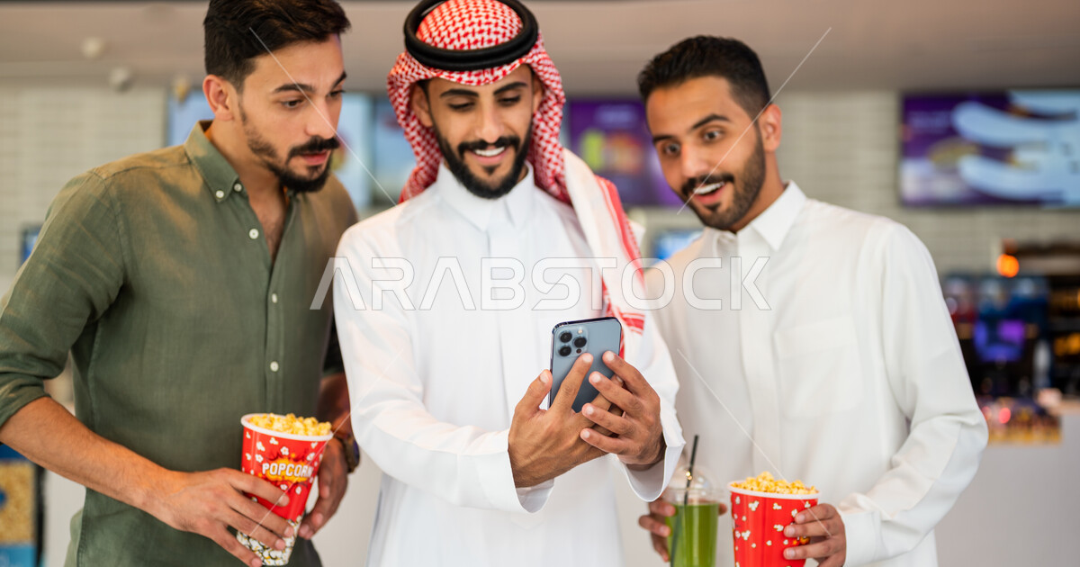 Arab Saudi Gulf friends in the reception hall inside the cinema, taking ...