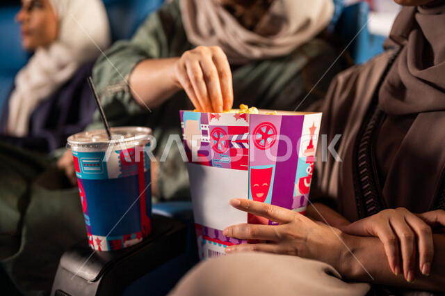 Saudi Arabian Gulf female friends sitting in the cinema, enjoying ...