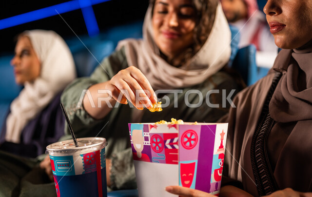 Saudi Arabian Gulf female friends sitting in the cinema, enjoying ...