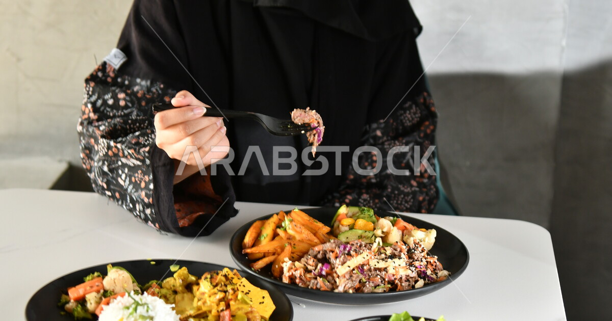 Close-up of the hand of a Saudi Arabian Gulf woman eating, a delicious ...