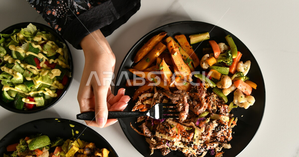 Close-up of the hand of a Saudi Arabian Gulf woman eating, a delicious ...