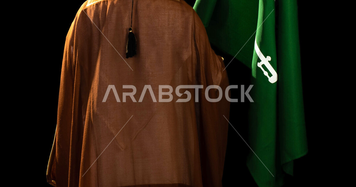 Portrait from the back of a Saudi Arabian Gulf man raising the flag of ...