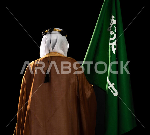 Portrait from the back of a Saudi Arabian Gulf man raising the flag of ...